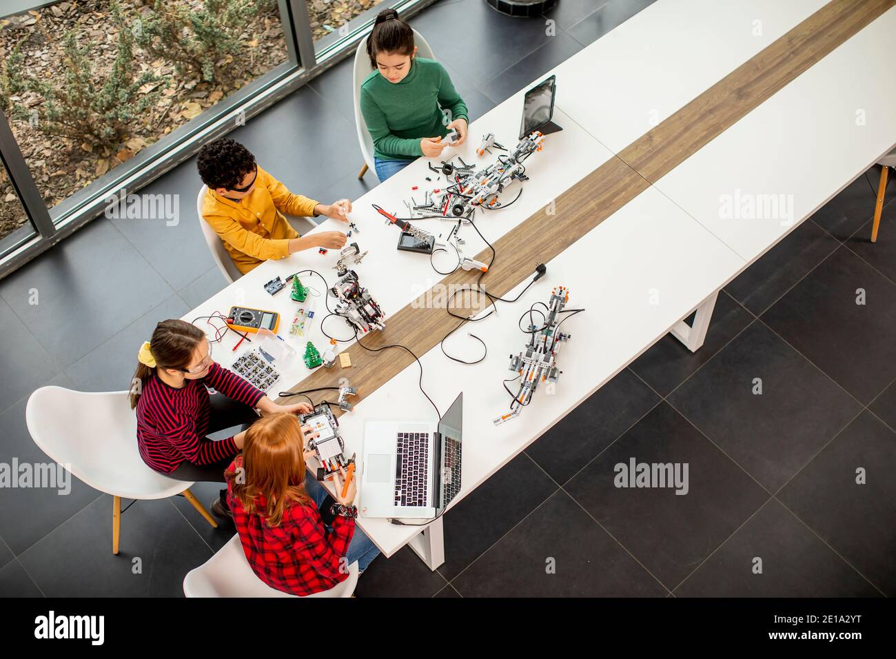 Overhead view at group of happy kids programming electric toys and ...