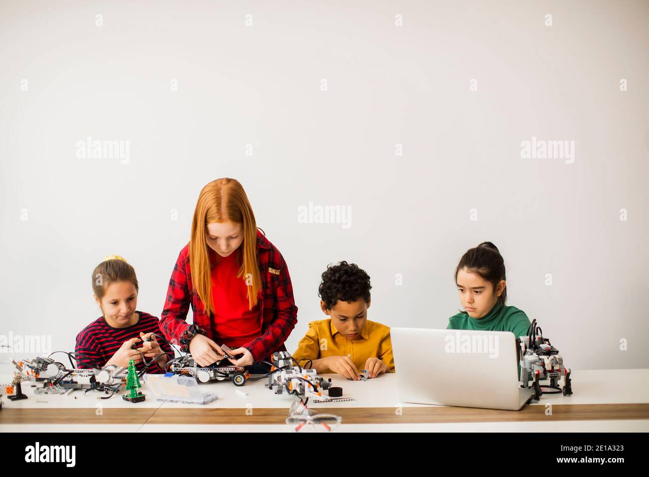 Group of happy kids programming electric toys and robots at robotics ...