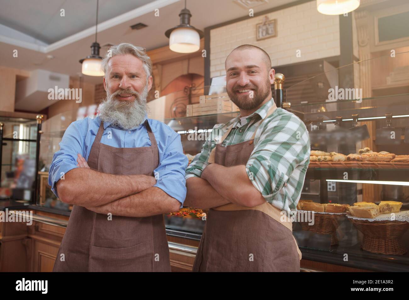 Cheerful father and son bakers enjoying working at their bakery store ...