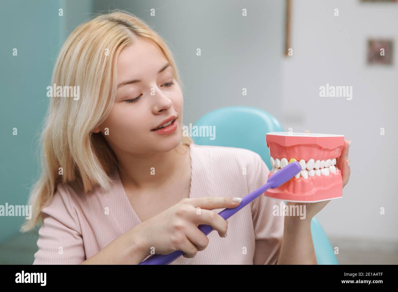 Lovely woman showing how to brush teeth correctly, holding jaw model ...