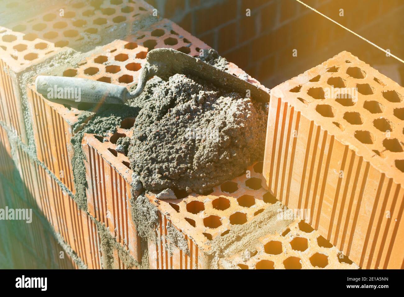 Spatula and cement mortar, red brick masonry, construction concept ...