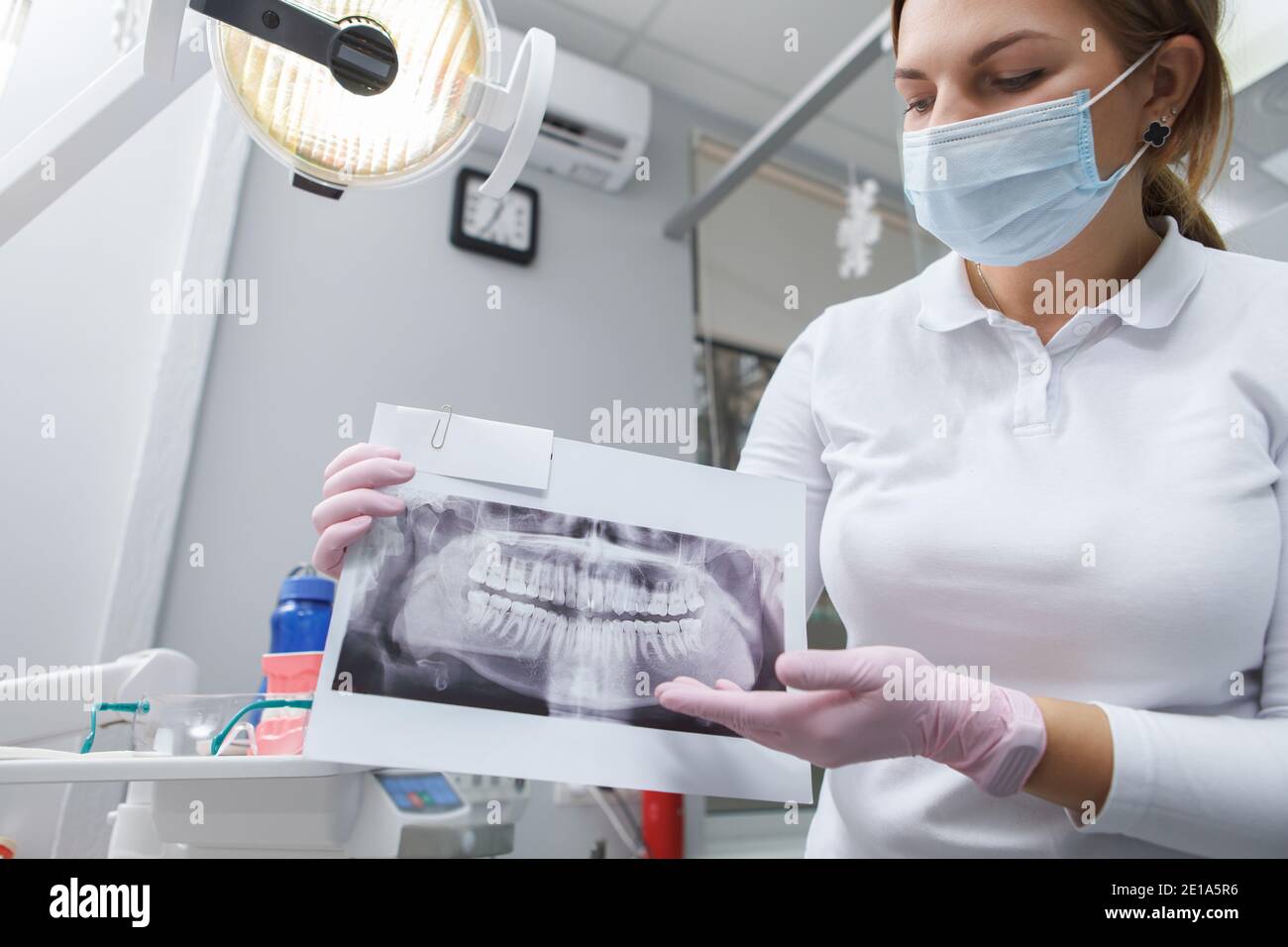Female dentist wearing medical face mask showing dental x-ray to the ...