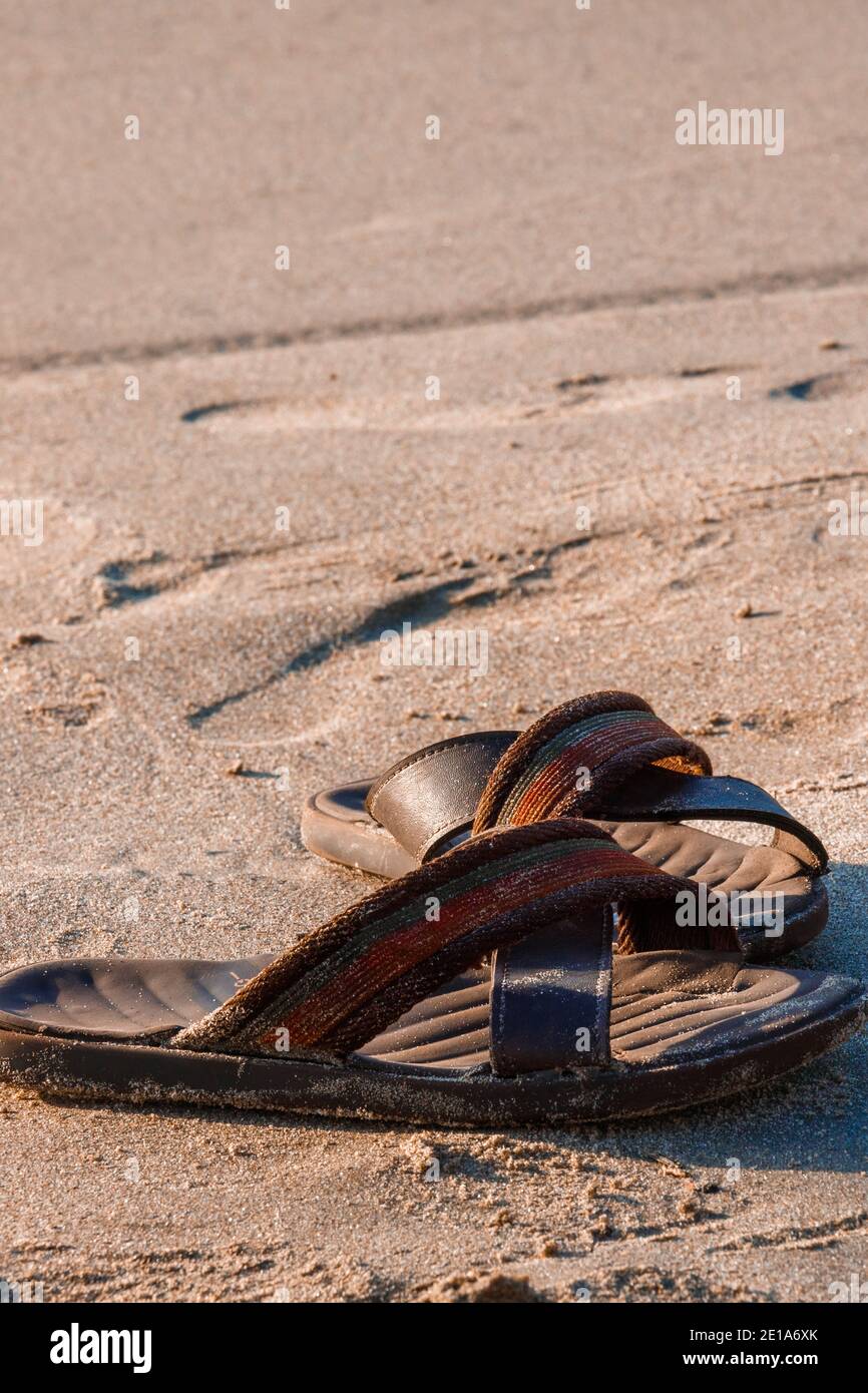 A pair of sandals or flip flops left by its traveler owner on the beach ...