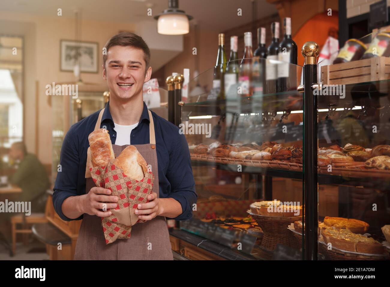 Happy handsome young man laughing, enjoying working at the bakery ...