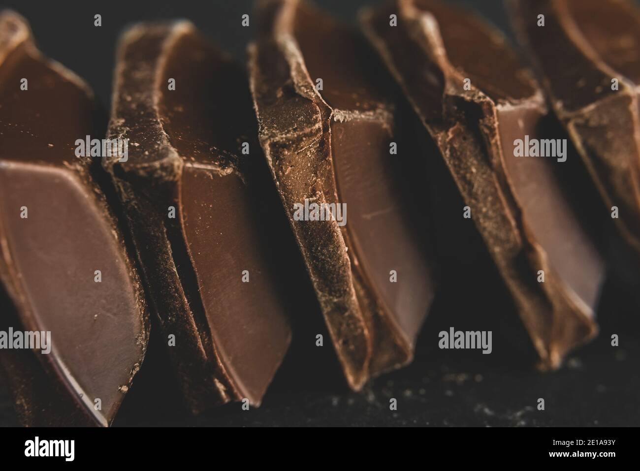 Broken dark chocolate blocks stack on black background Stock Photo - Alamy