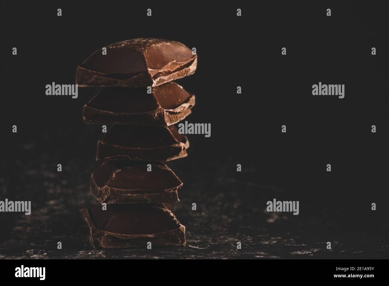 Broken dark chocolate blocks stack on black background Stock Photo - Alamy