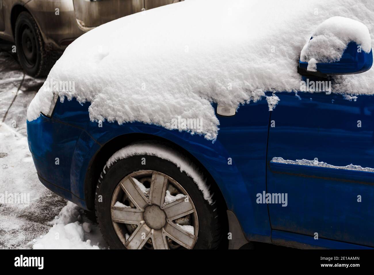 Blue car bumper covered with thick snow layer. Cold cyclone. Transport ...