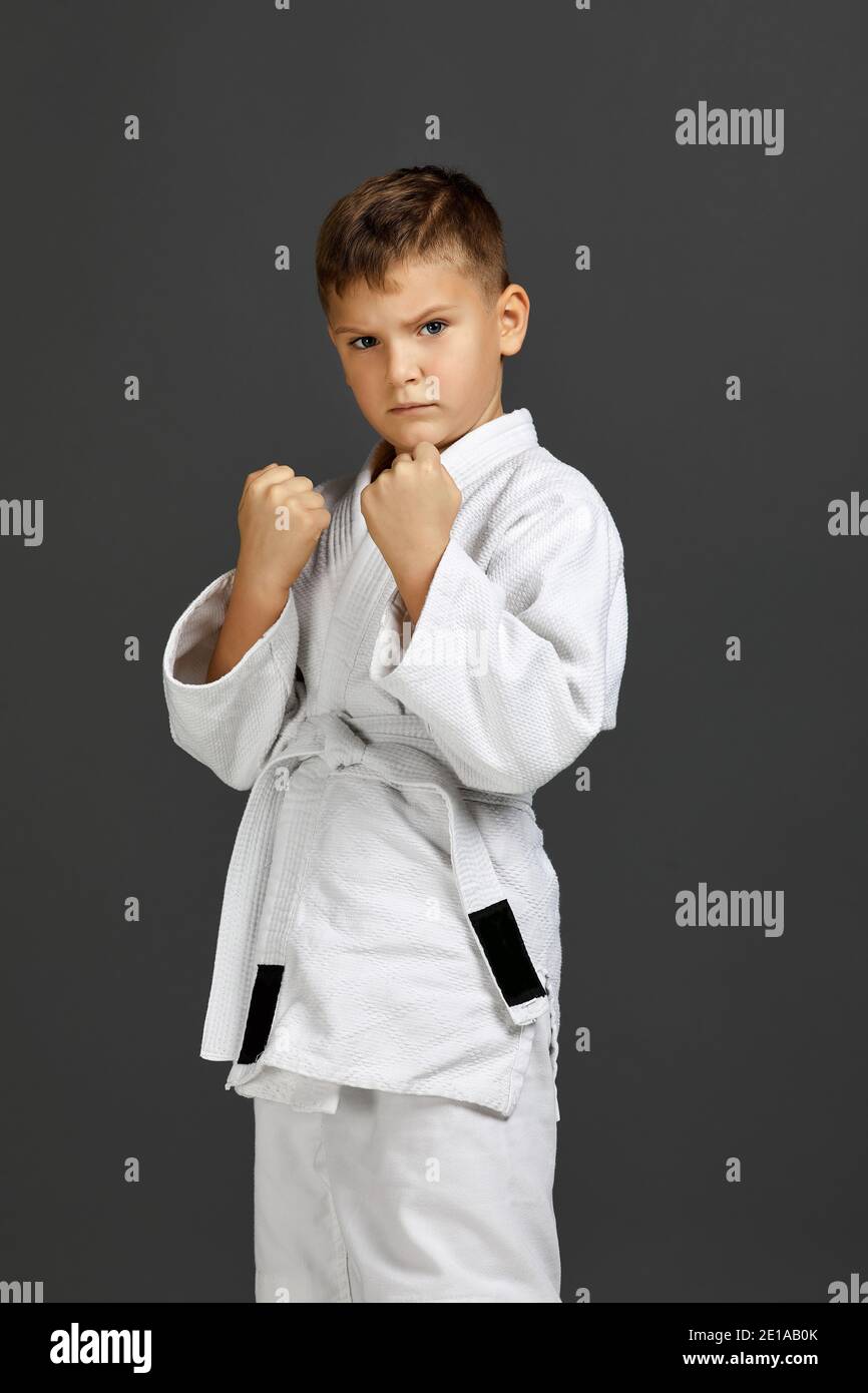 little child boy in a white karate kimono. Karate fighter ready to ...