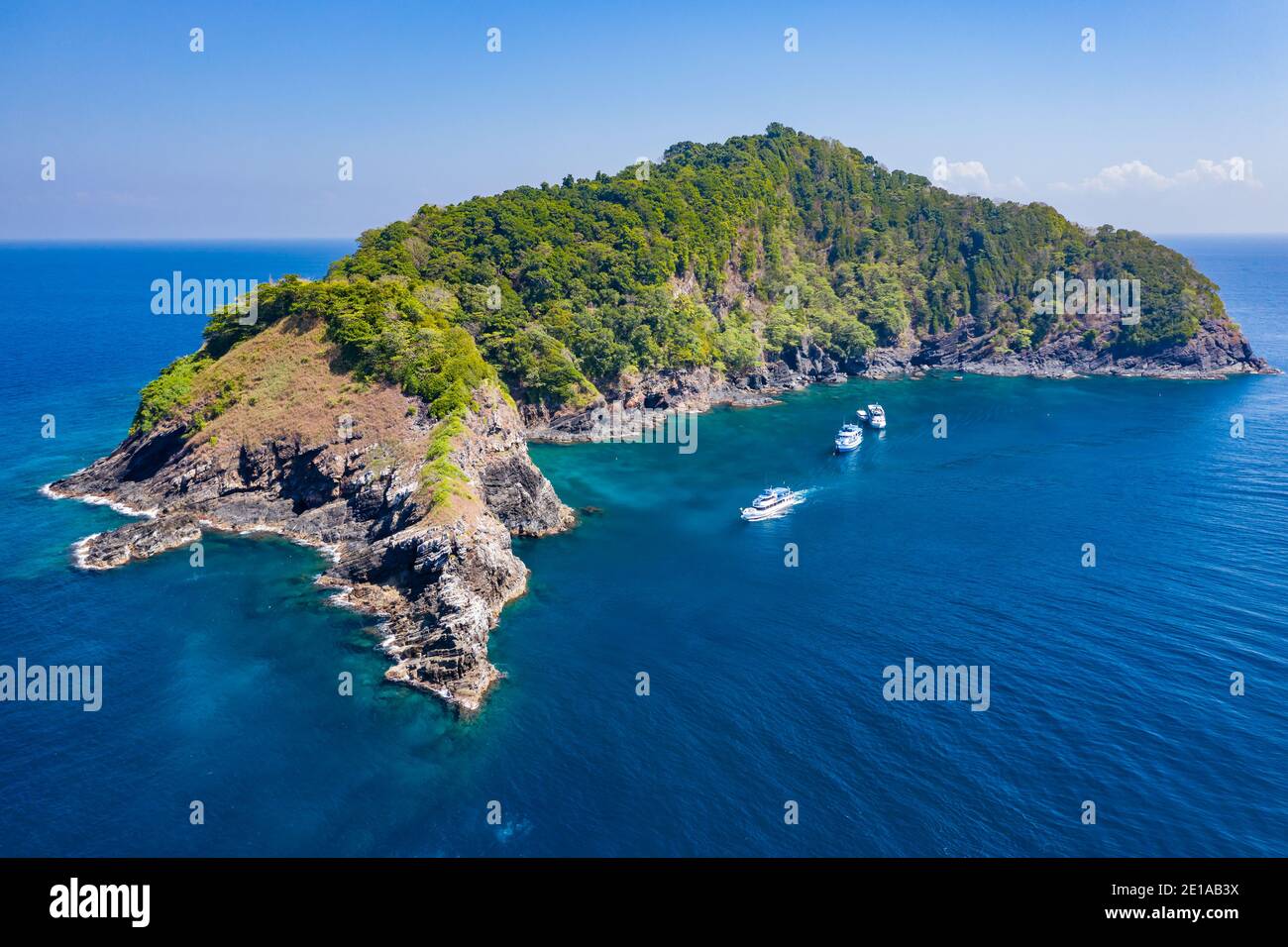 SCUBA diving boats and diver around a rugged, remote tropical island ...