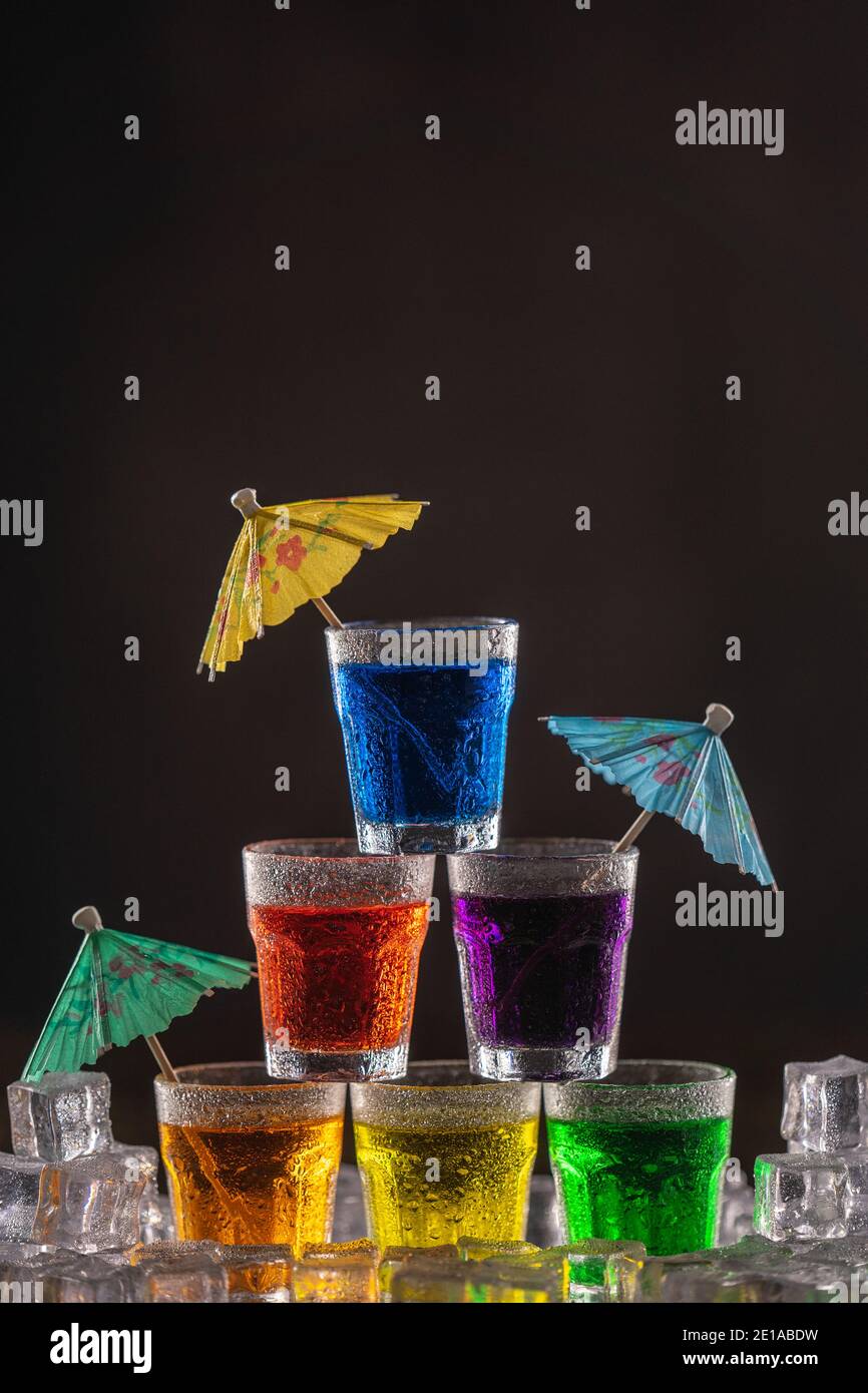 Pyramid of shots with colorful alcohol, decorated with umbrellas for ...