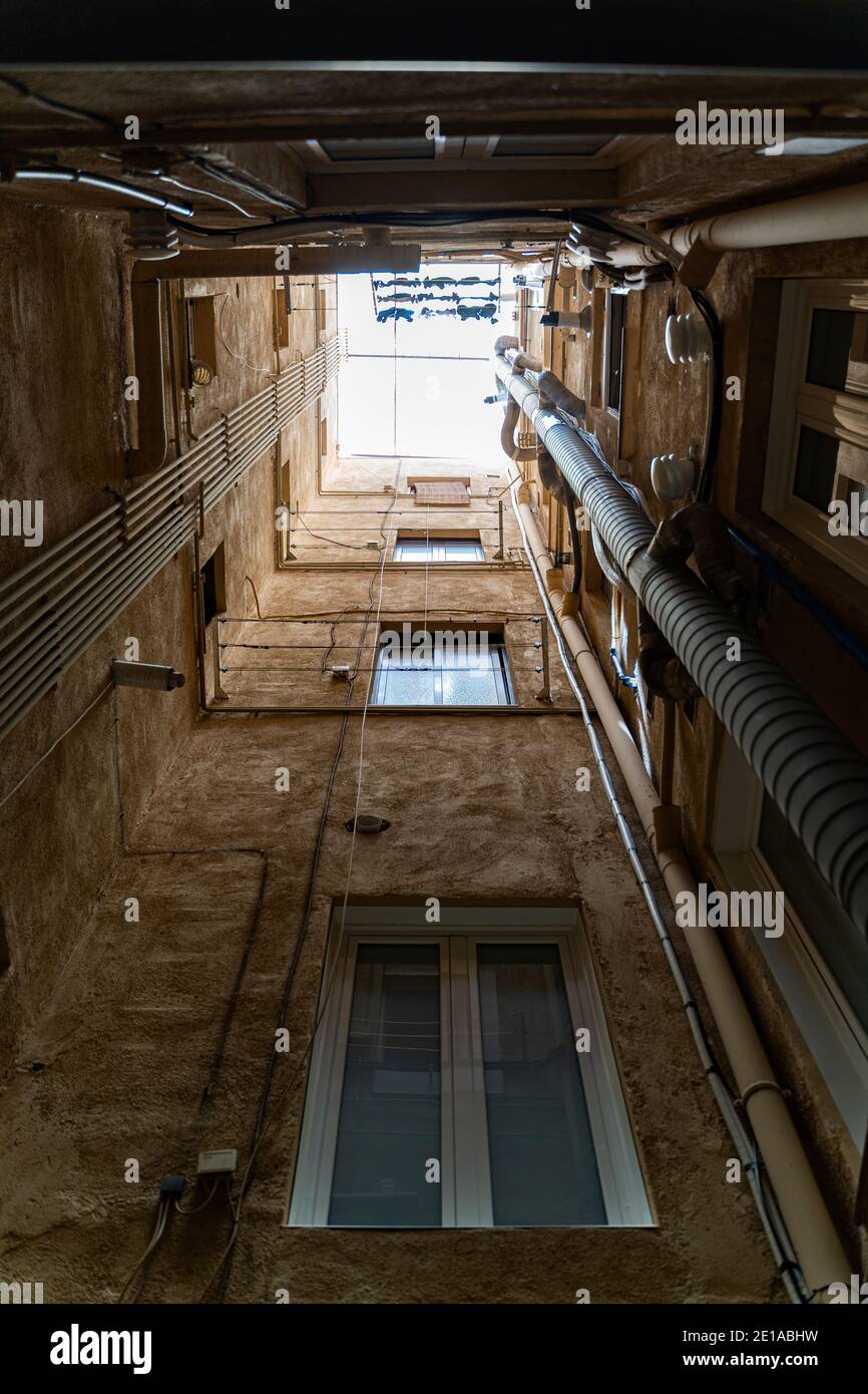 Well in courtyard of old buildings with windows, pipes and daylight ...