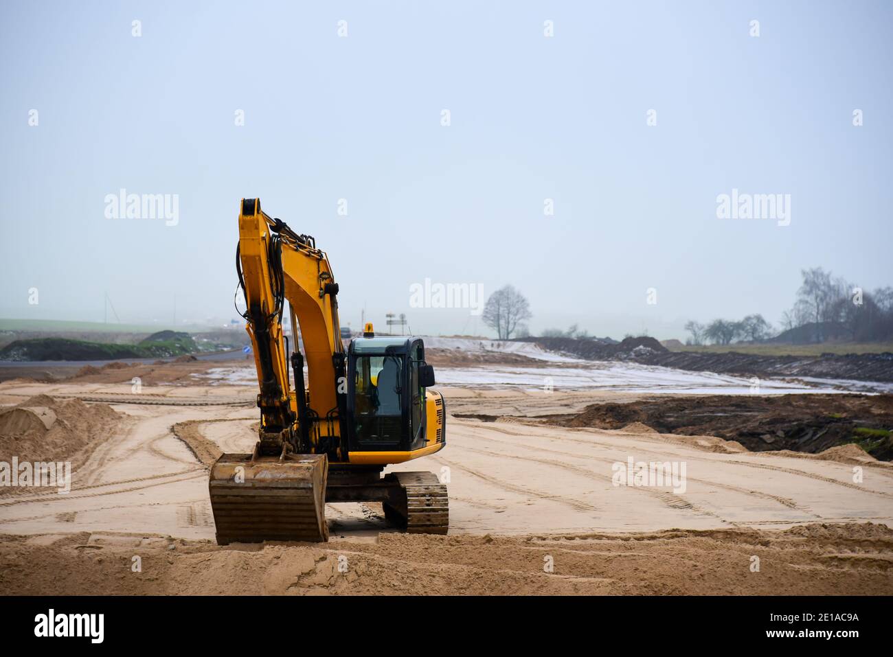 Excavator digs sand at road construction Stock Photo - Alamy