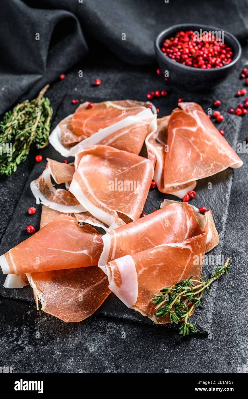 Spanish jamon Serrano with thyme, cured ham. Black background. Top view ...