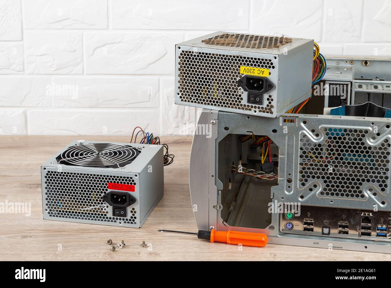 New power supply unit and a screwdriver near tower case with removed ...
