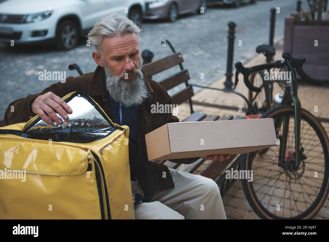 Senior delivery guy putting cardboard box package into his delivery ...