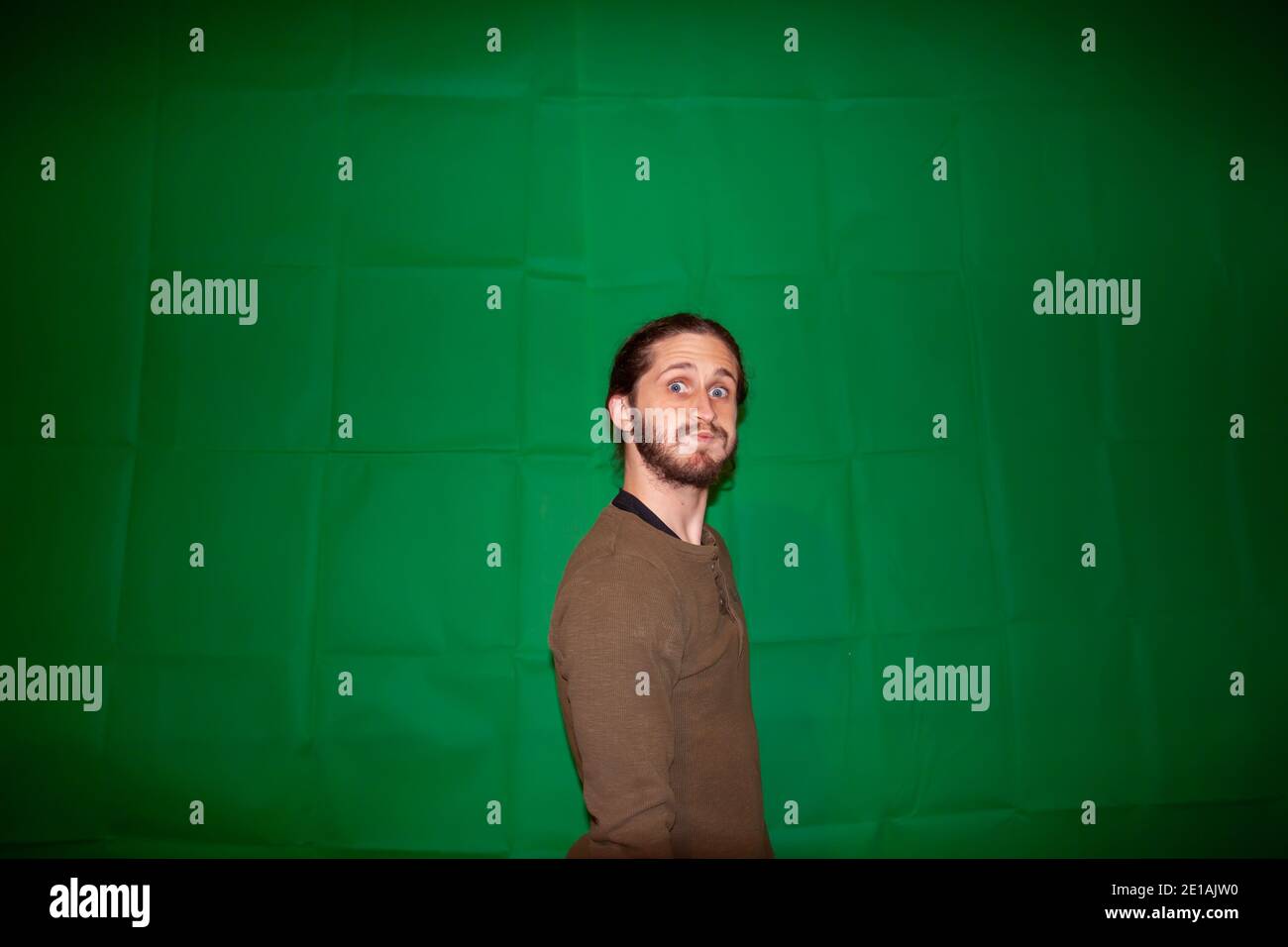 Shot of a young man with a beard, posing with eyes fully opened, and a ...