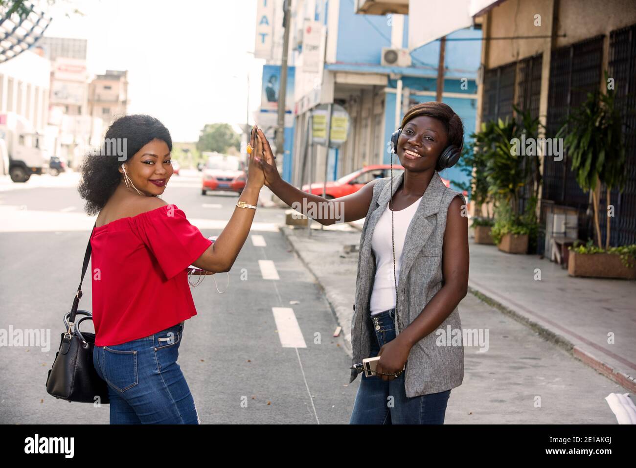 group of two happy smiling friends with headphones listening to music ...
