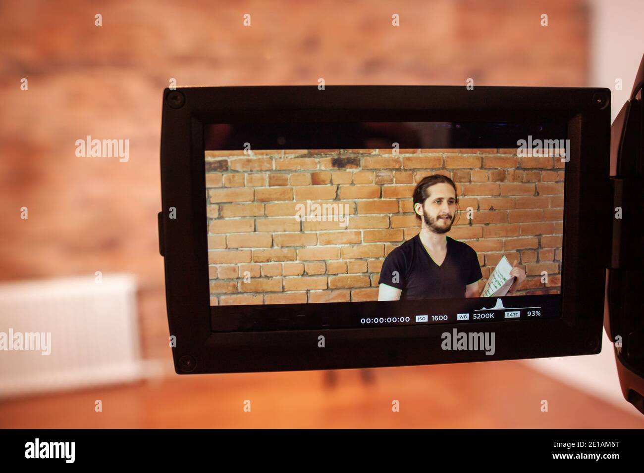 Behind the scene picture of a young man, recording a video with papers ...