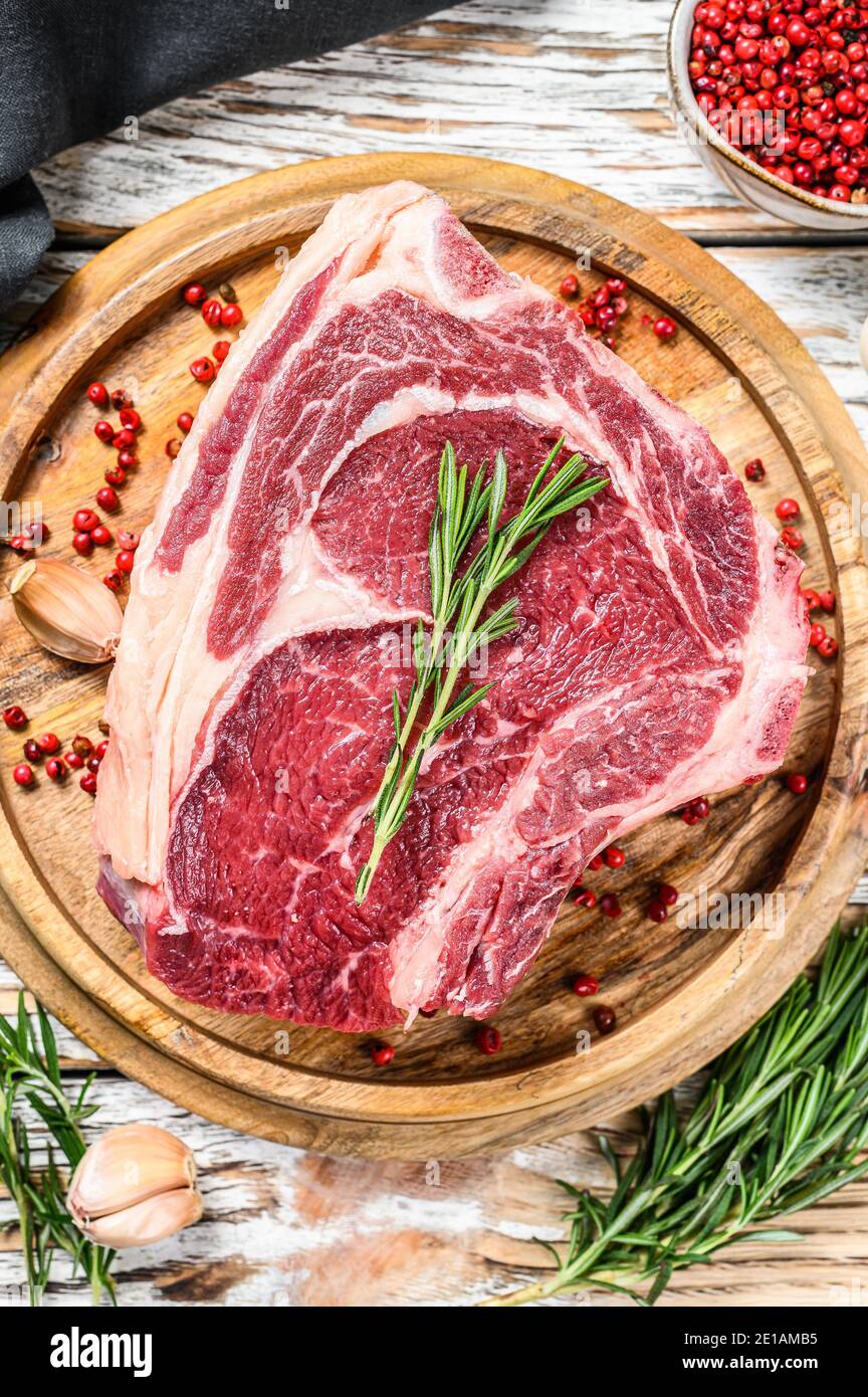 Raw cowboy steak or ribeye on the bone on a cutting board. Marble beef ...