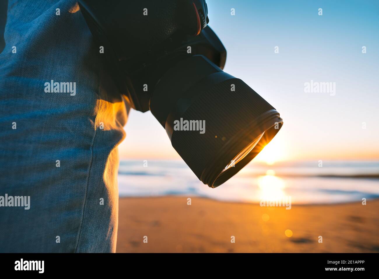 Professional photographer with his camera on the beach at sunset ready ...