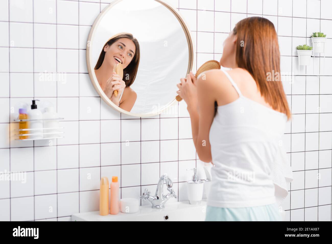 cheerful woman singing with hairbrush near mirror in bathroom Stock ...