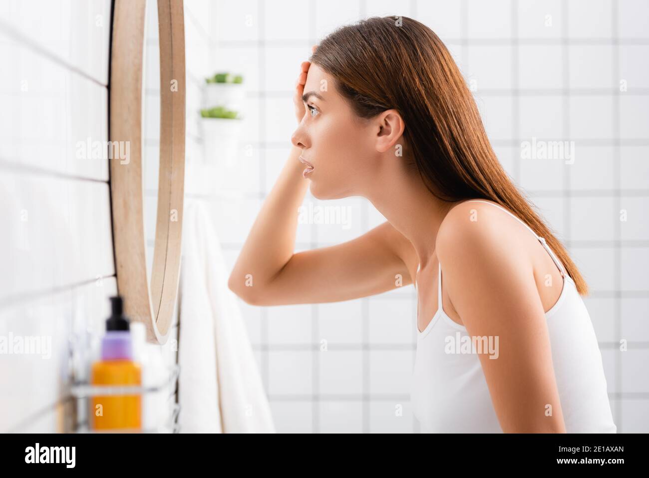 side view of worried young woman touching forehead while looking in ...