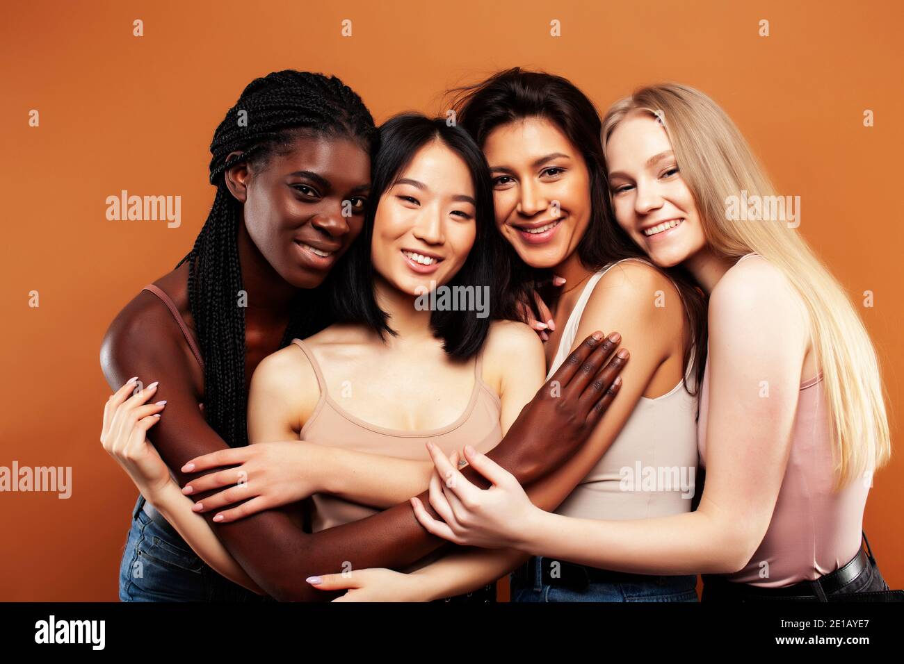 young pretty asian, caucasian, afro woman posing cheerful together on brown background ...