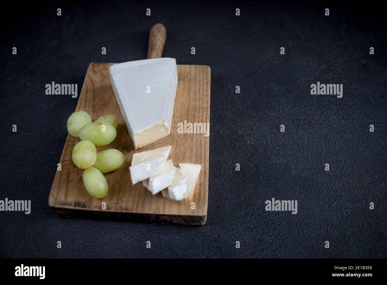 White goat cheese wih green grape on a black background. Fresh goat ...