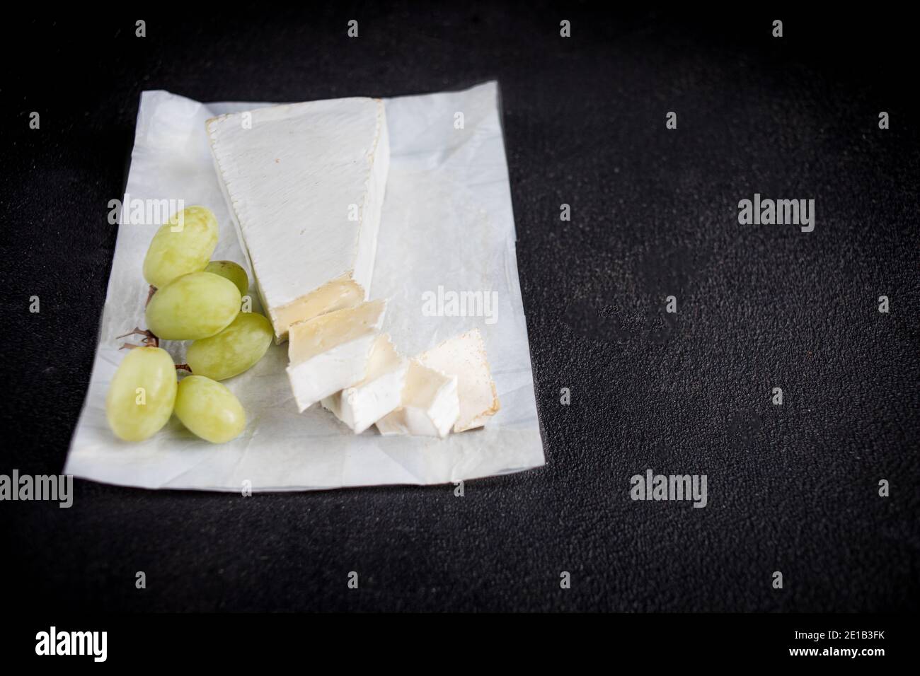 White goat cheese wih green grape on a black background. Fresh goat ...