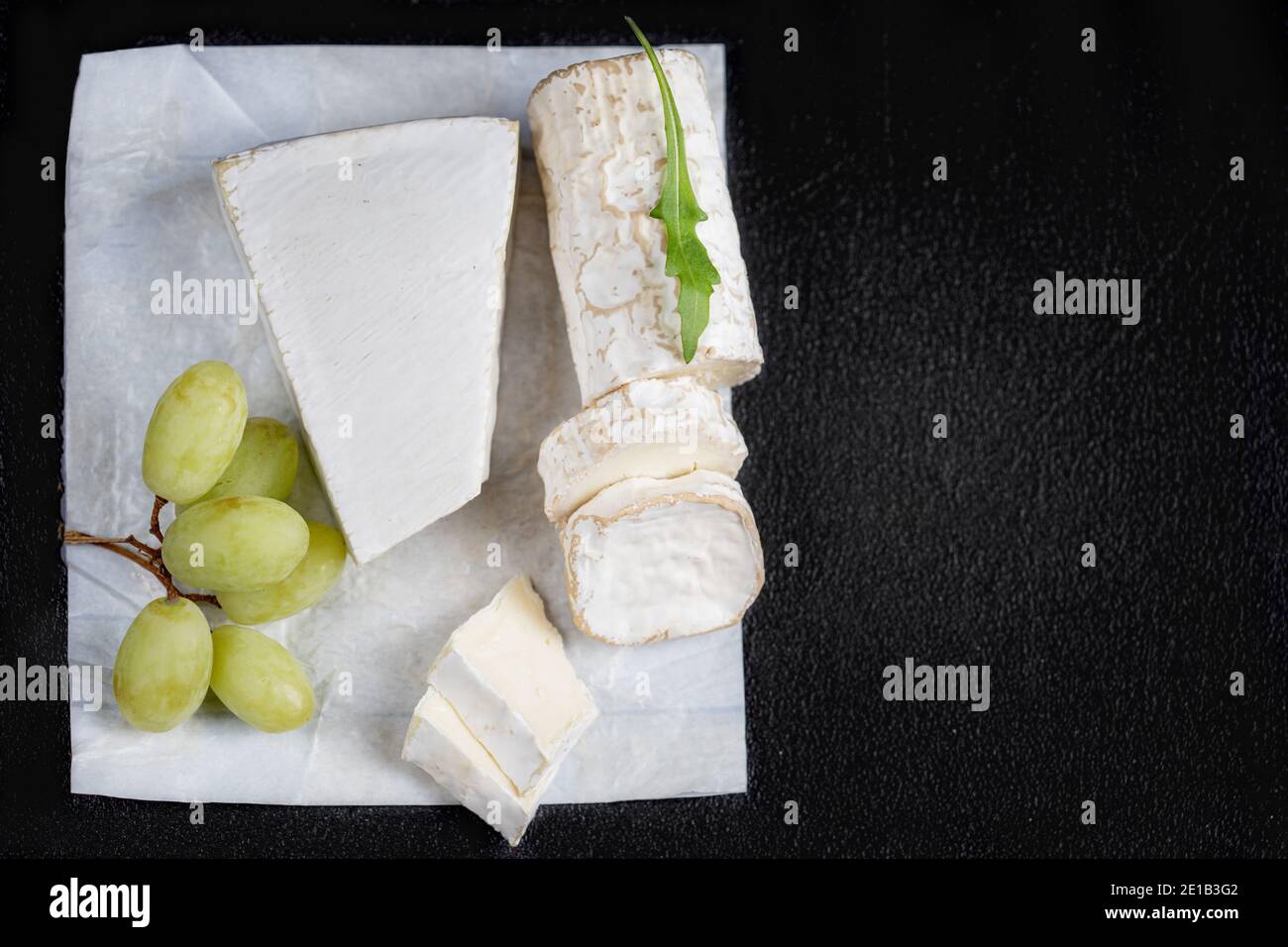 White goat cheese wih green grape on a black background. Fresh goat ...