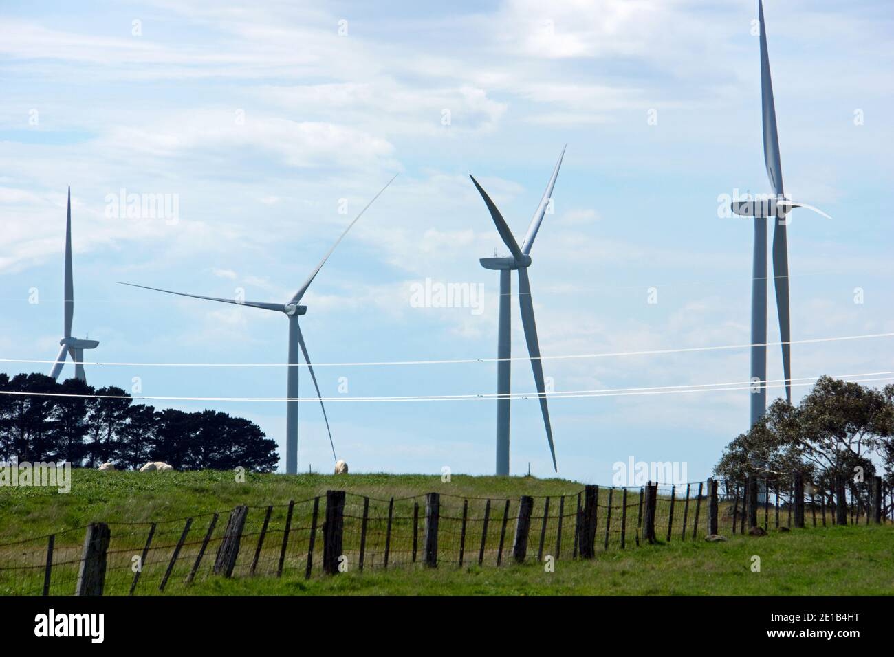 Wind turbines generating electricity from wind energy with fence line ...