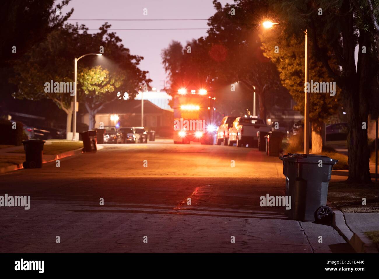 A night time collection of trash by a garbage truck in a suburban ...