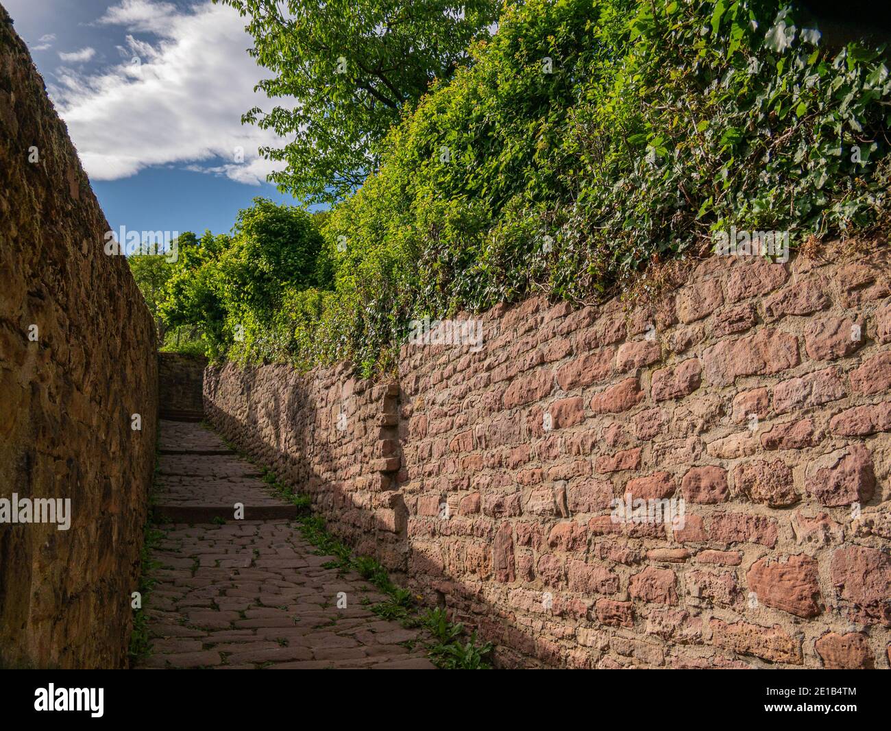 A narrow path with small steps between two stone walls Stock Photo - Alamy