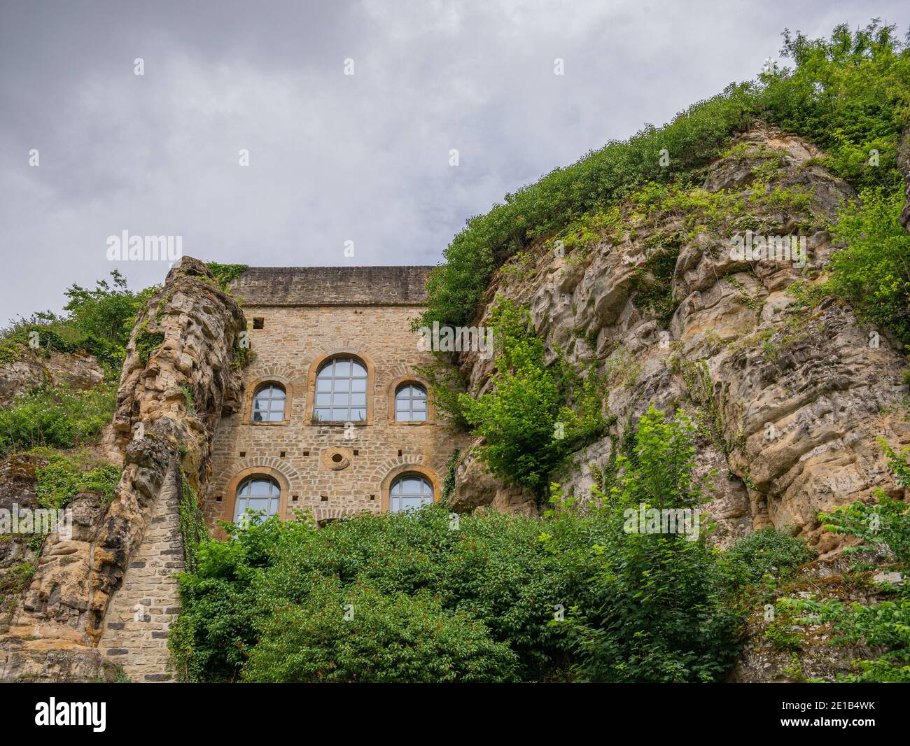 An old stone house facade with window between two rocks Stock Photo - Alamy