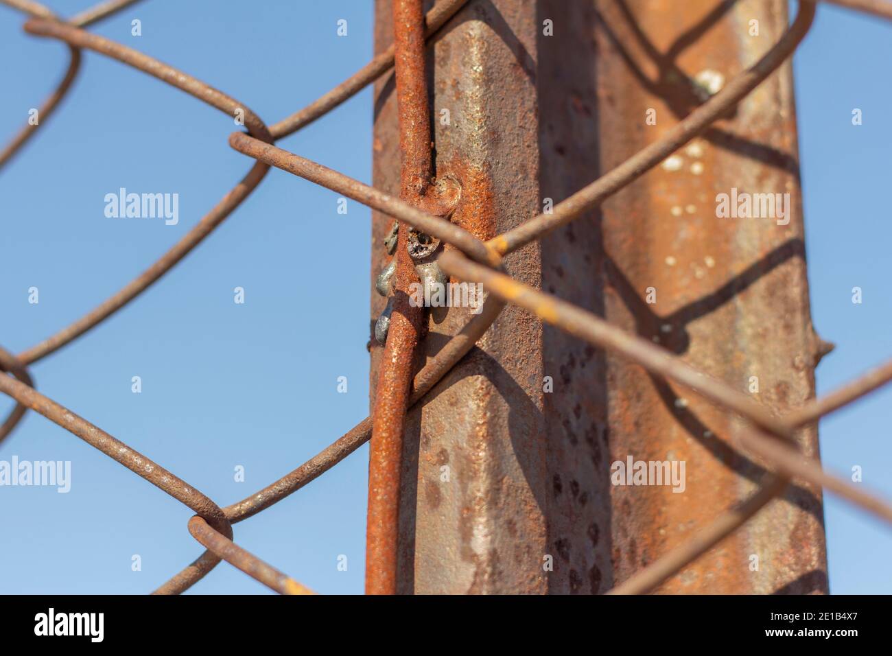 Close-up on a rusty metal pole rusty steel mesh chain link.An old fence ...