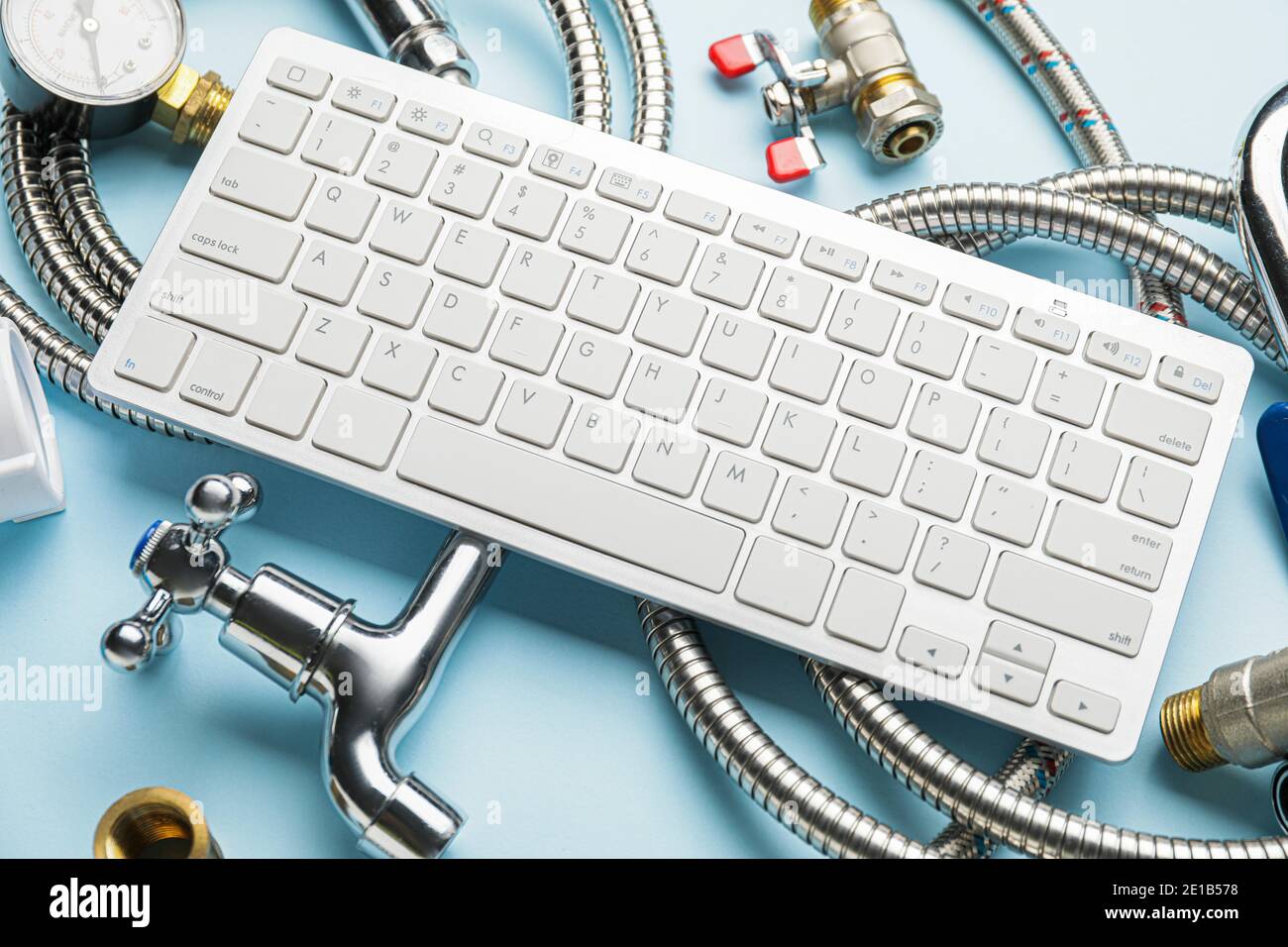 Plumbing items and computer keyboard on color table Stock Photo - Alamy