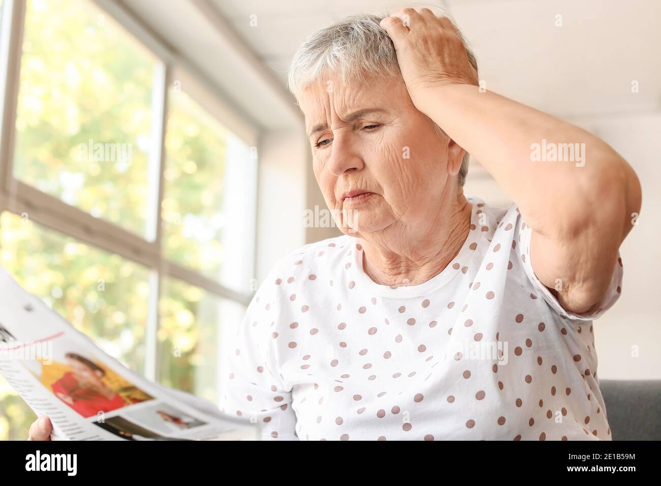 Stressed senior woman reading newspaper at home Stock Photo - Alamy