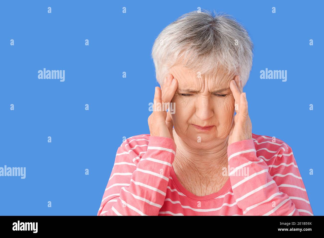 Stressed senior woman suffering from headache on color background Stock ...