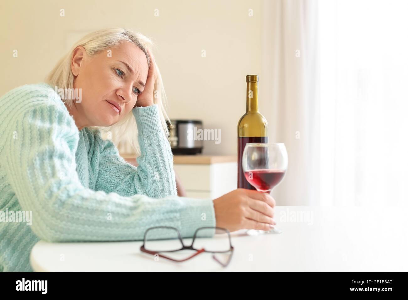 Stressed mature woman drinking wine at home Stock Photo - Alamy