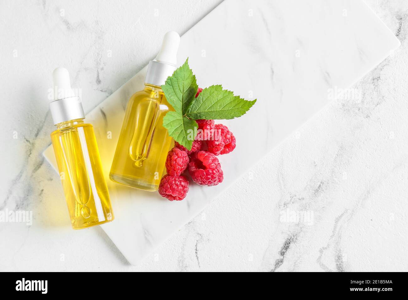 Bottles of raspberry essential oil on light background Stock Photo - Alamy