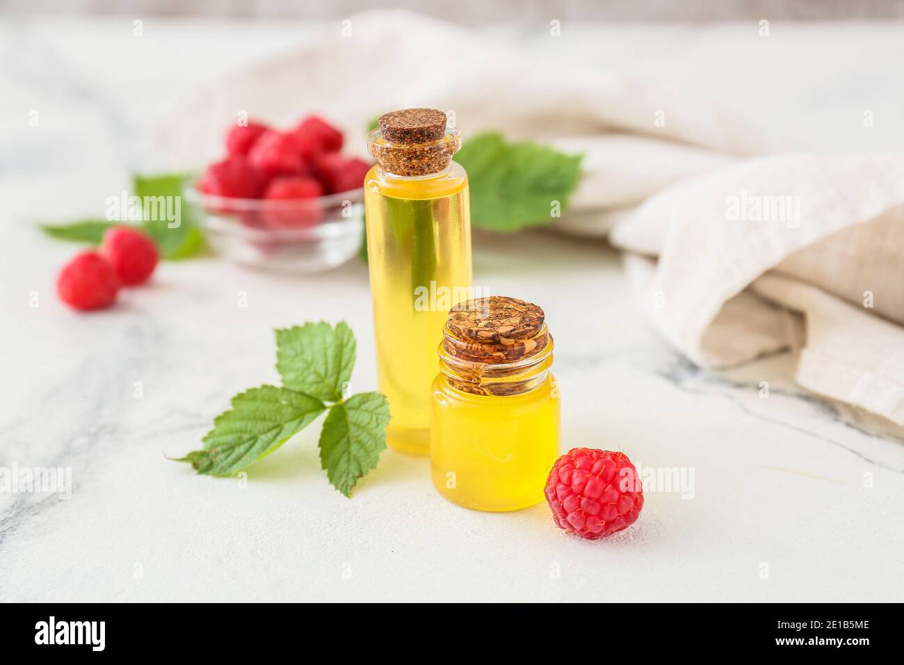 Bottles of raspberry essential oil on light background Stock Photo - Alamy