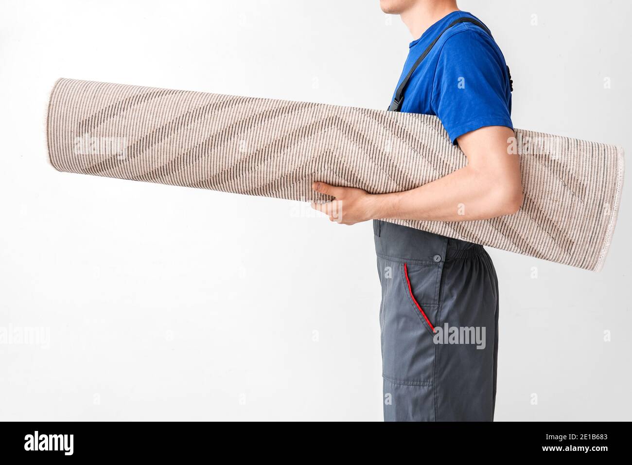 Worker with rolled carpet on white background Stock Photo - Alamy