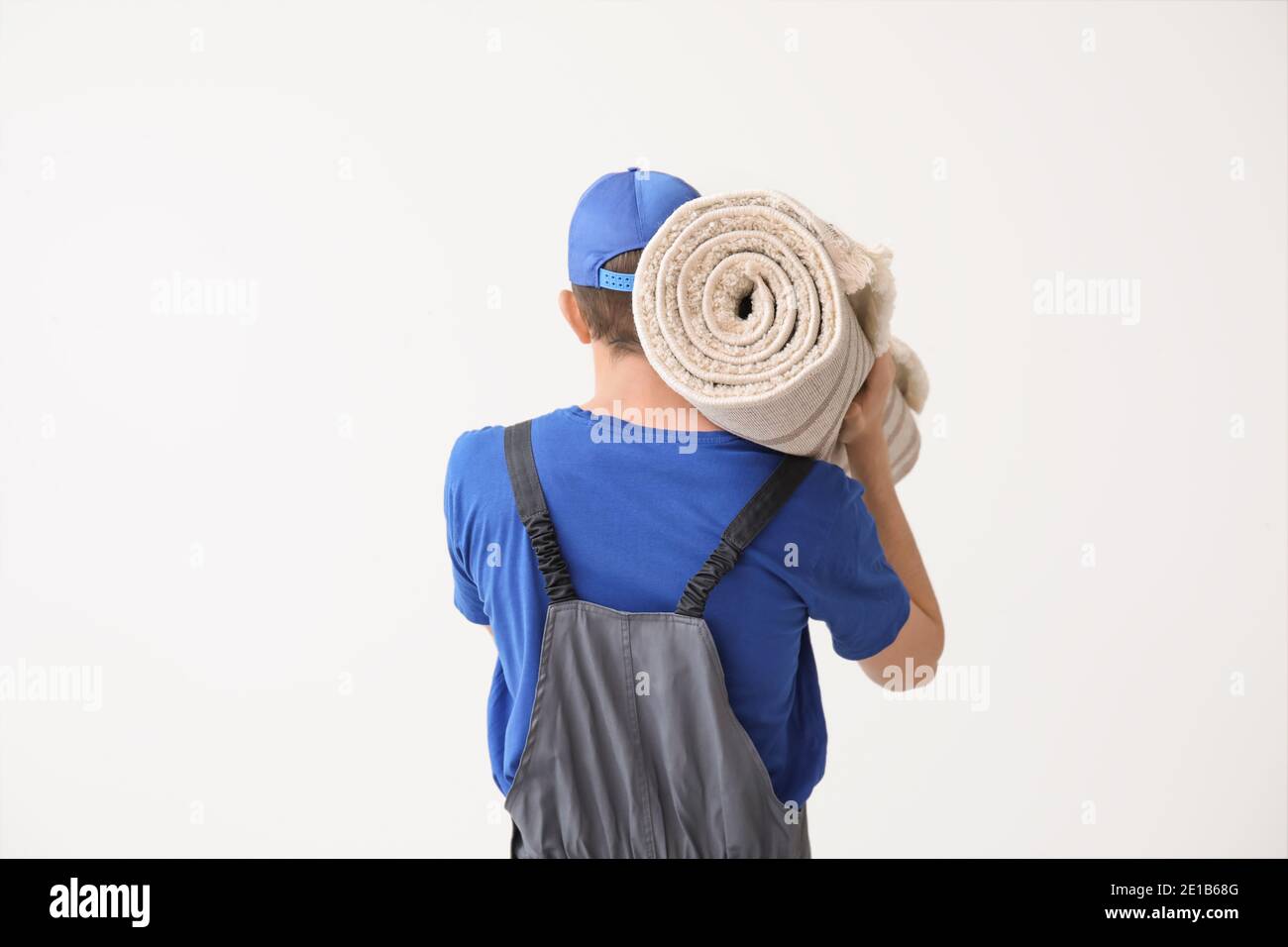 Worker with rolled carpet on white background Stock Photo - Alamy