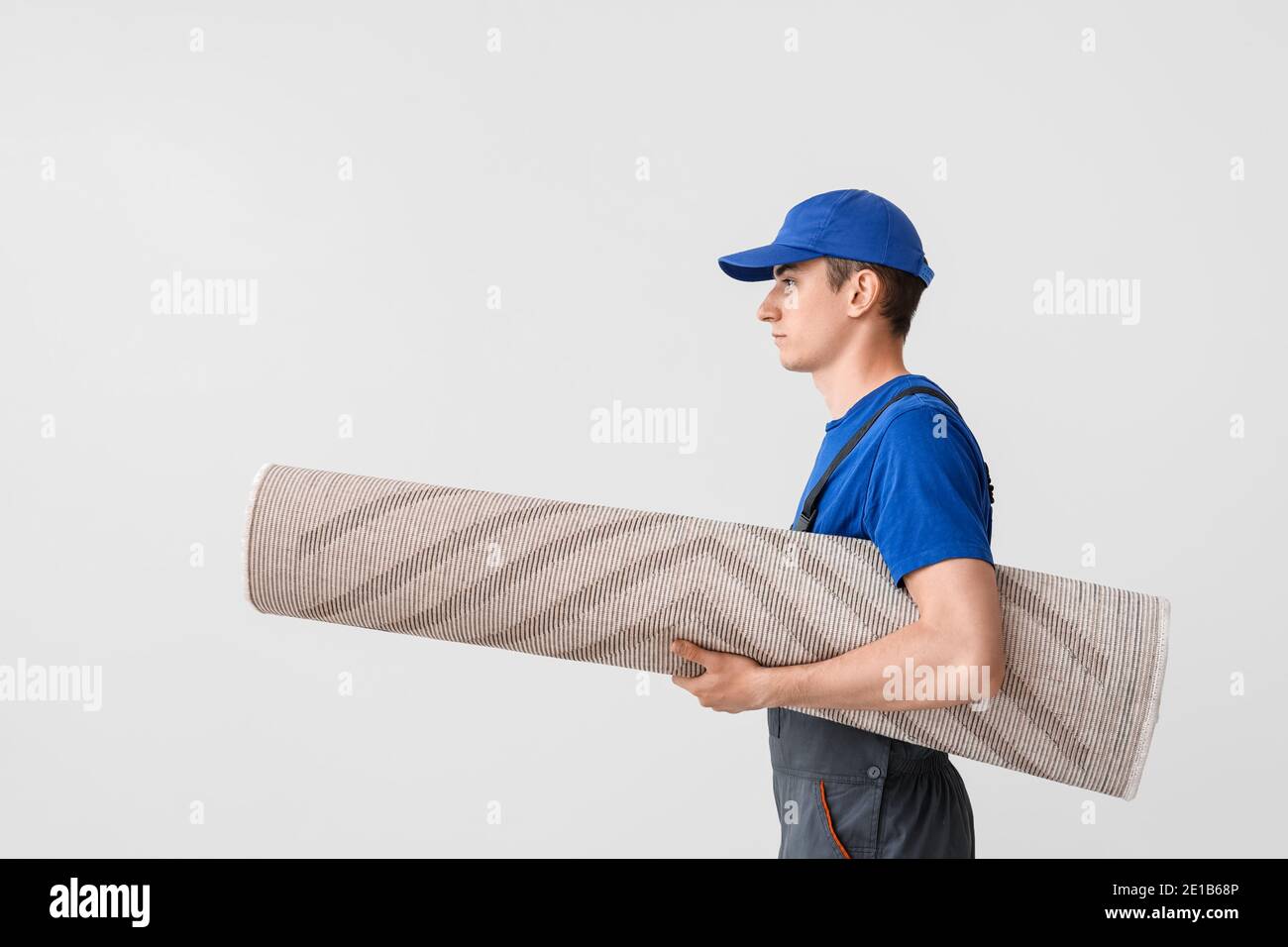 Worker with rolled carpet on white background Stock Photo - Alamy