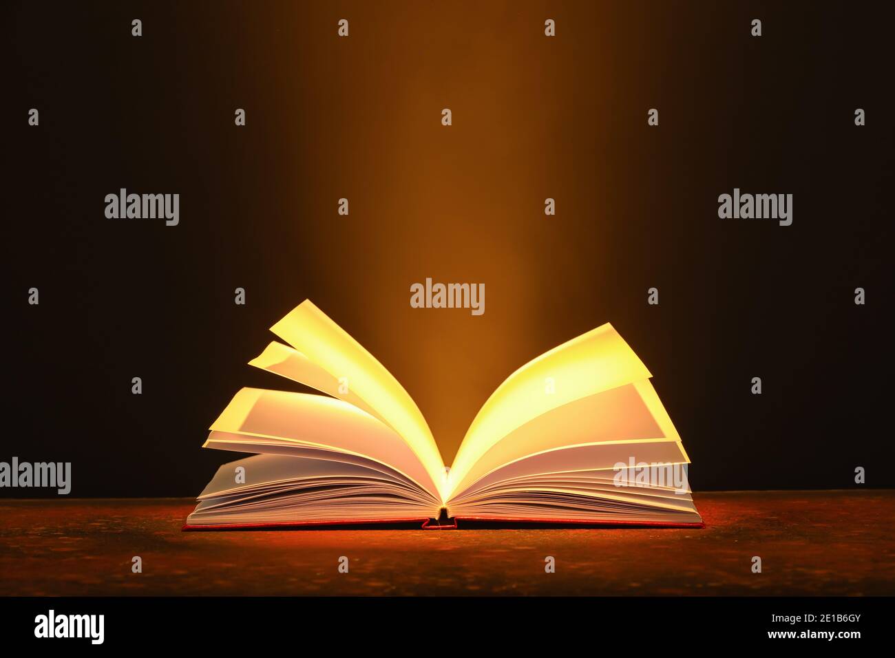 Open book on table against dark background Stock Photo - Alamy