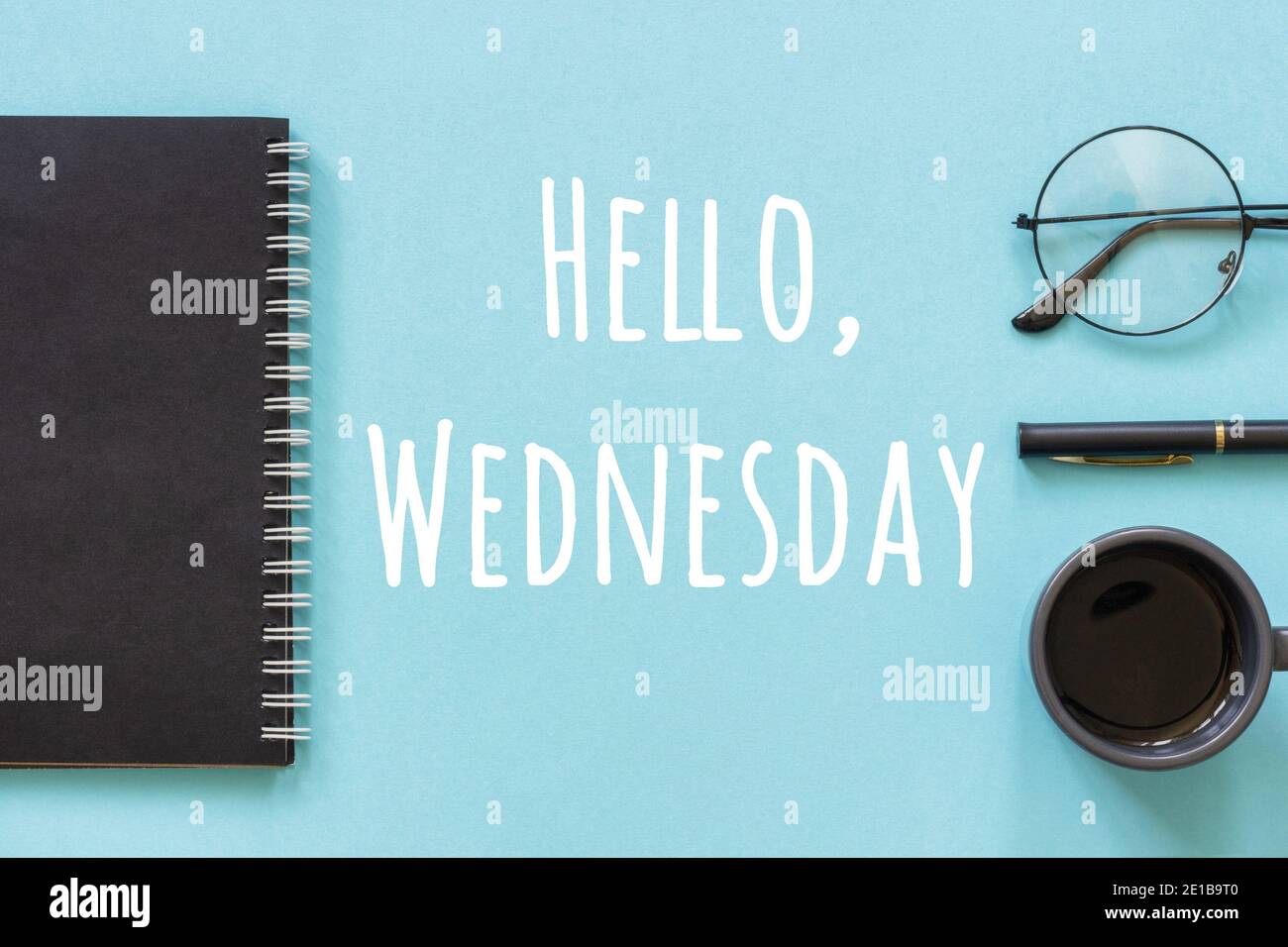 Hello Wednesday words in black notepad, pen, cup of coffee and reeding ...