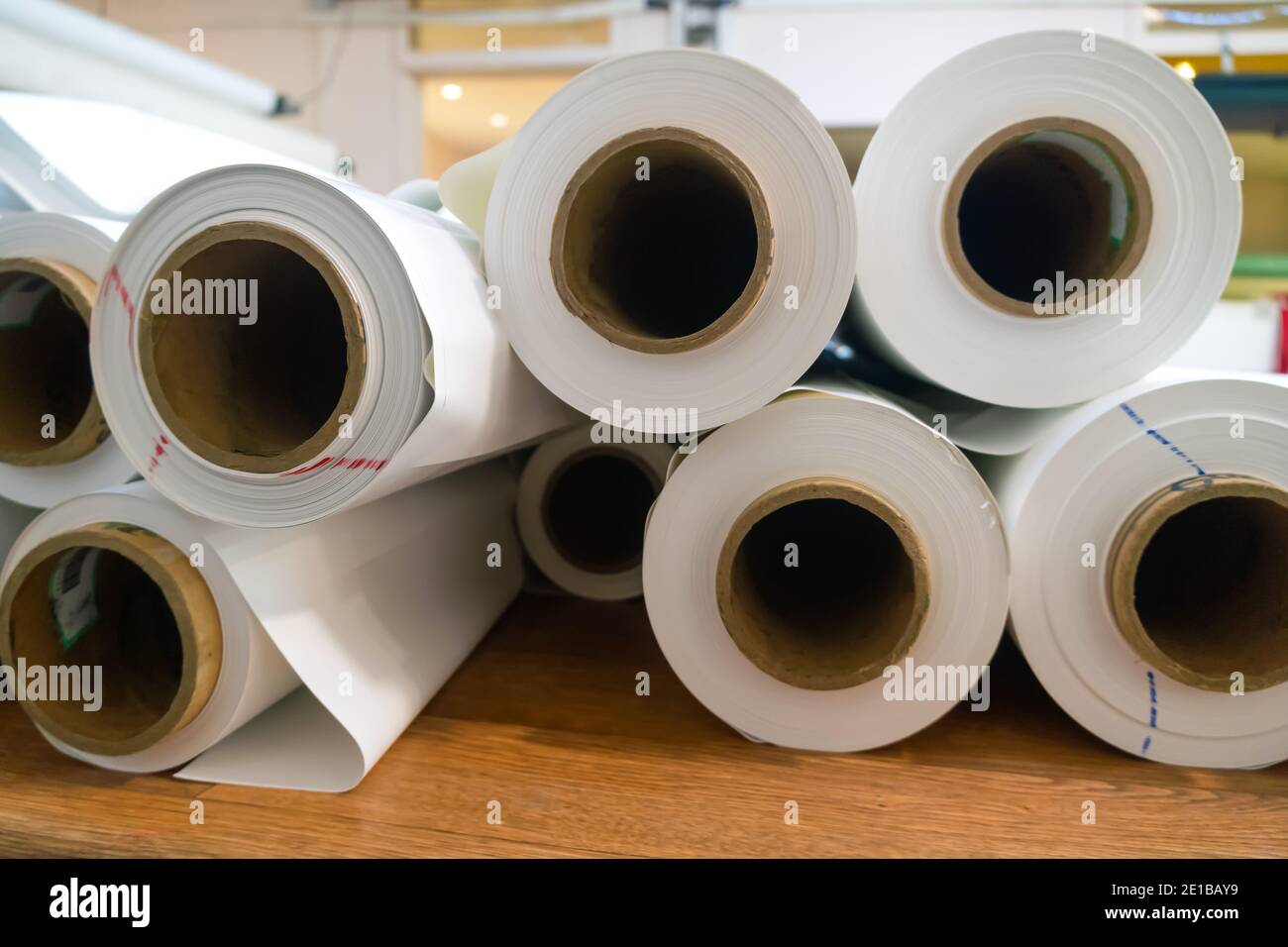 Many white rolls of PVC film are on the table in the workshop for the ...