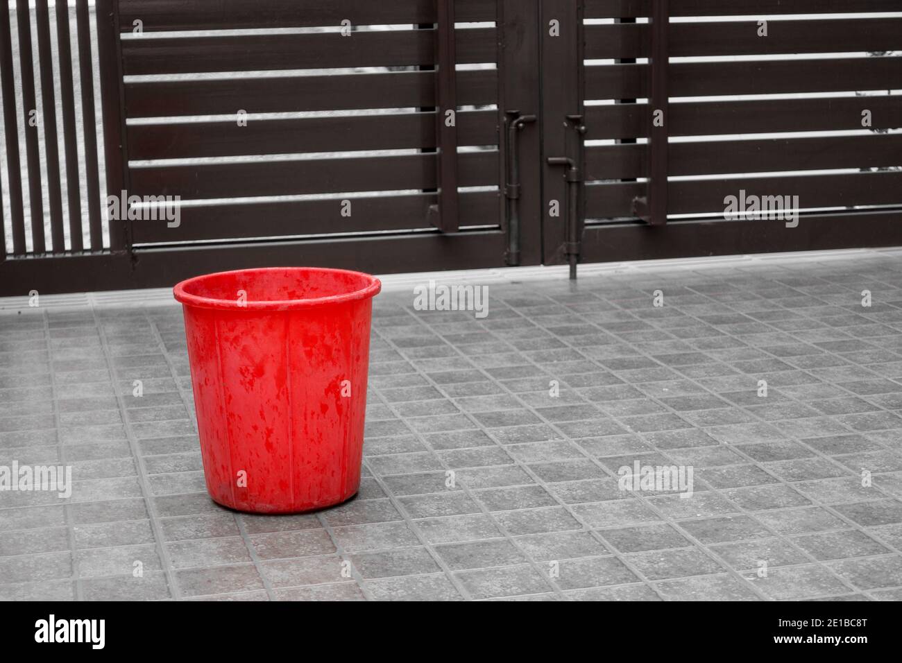 A close up shot of small red bucket on the tile floor Stock Photo - Alamy