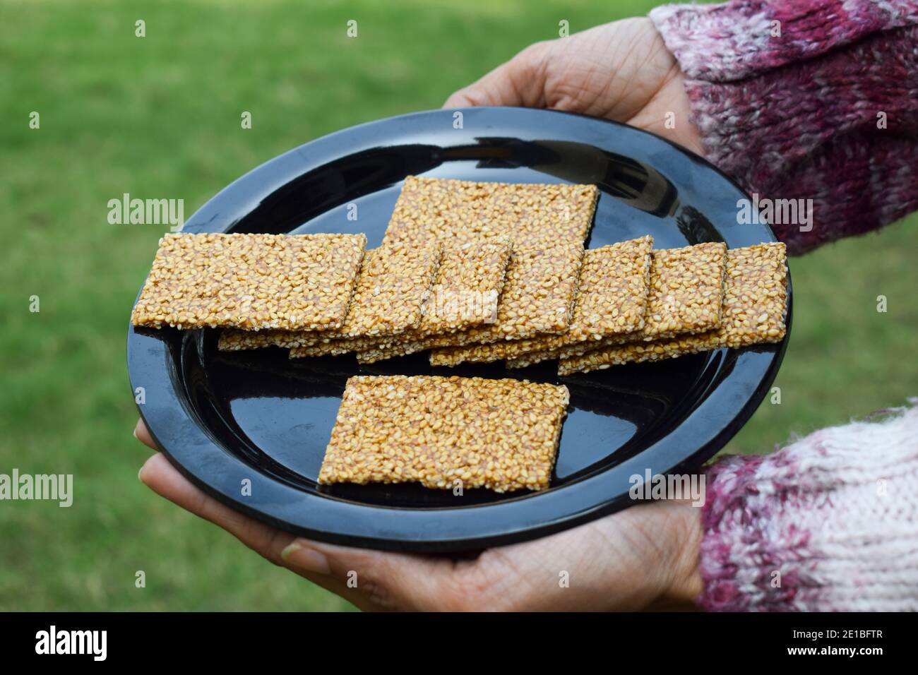 Female hand holding Winter special sweet dish of White sesame and ...