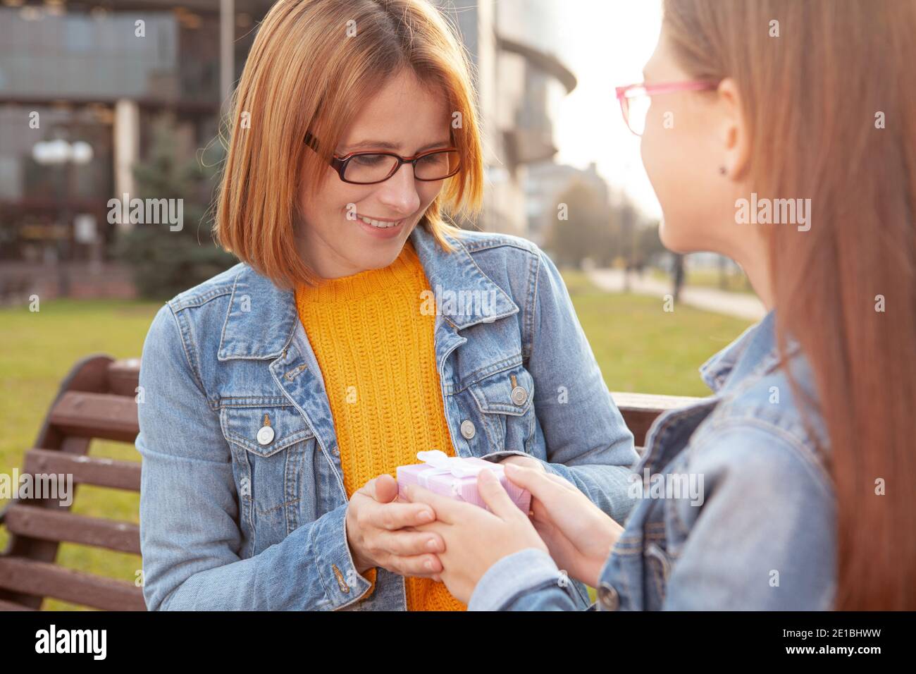 Happy mature woman receiving a present from her young daughter. Little ...